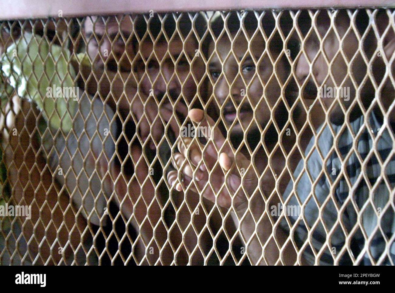 Iraqi detainees peer out of a cell at the Al-Ma'qal prison in Basra ...