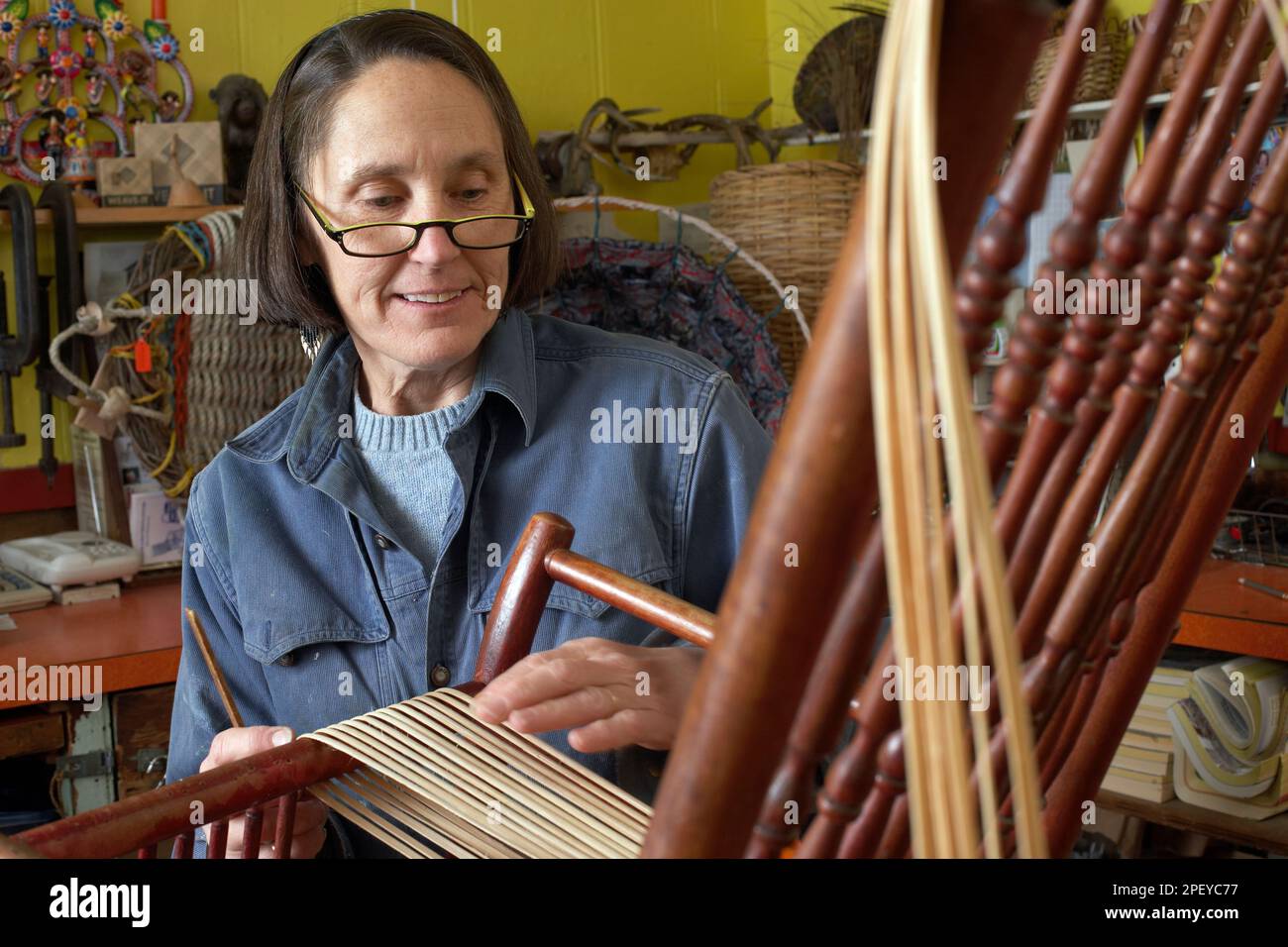 Female artisan weaves new caning onto an antique rocking chair Stock ...