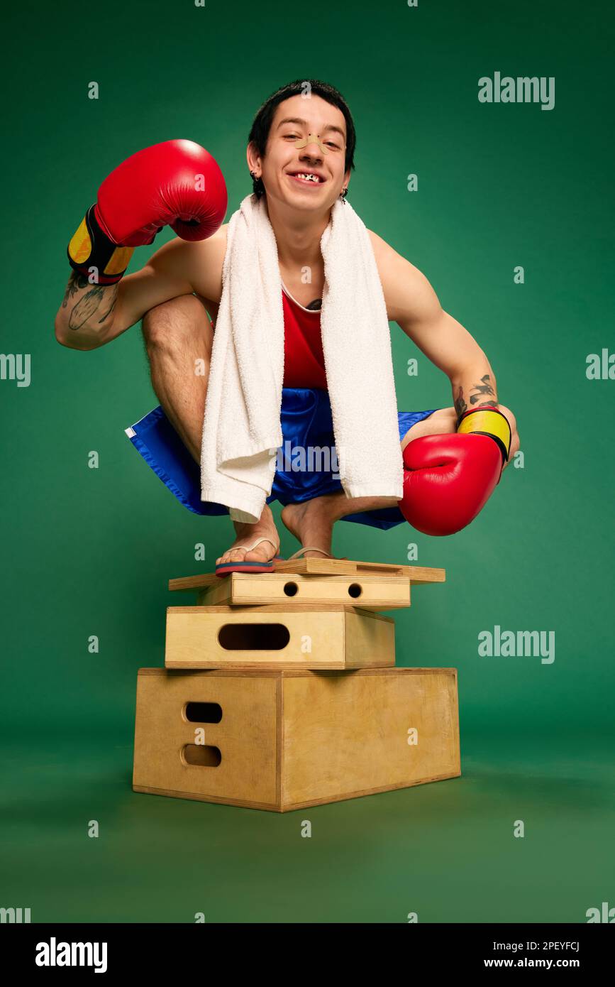 Portrait of young boxer in boxing gloves, squatting and posing over ...