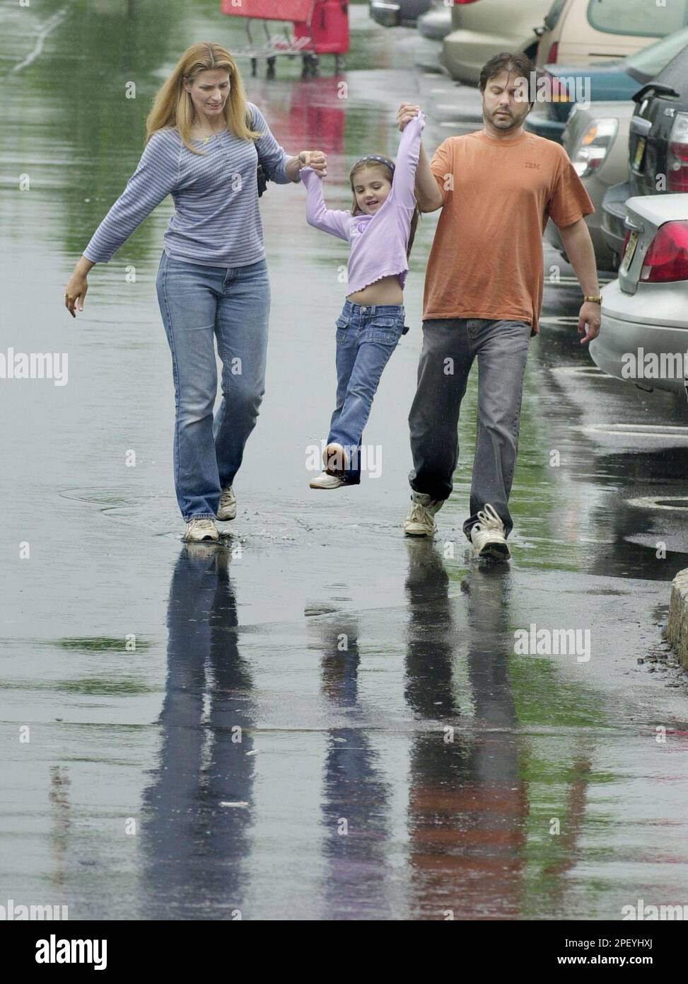 Donna and Steve Sileo lift their daughter, Gina, 5, over a puddle in a ...