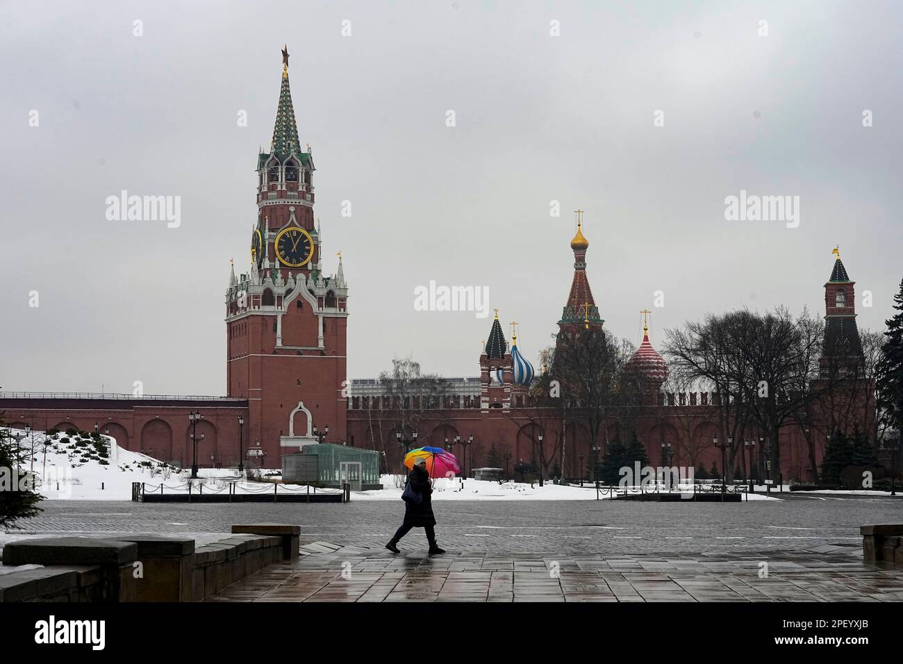 A pedestrian holding an umbrella walks under the rain at the Kremlin ...