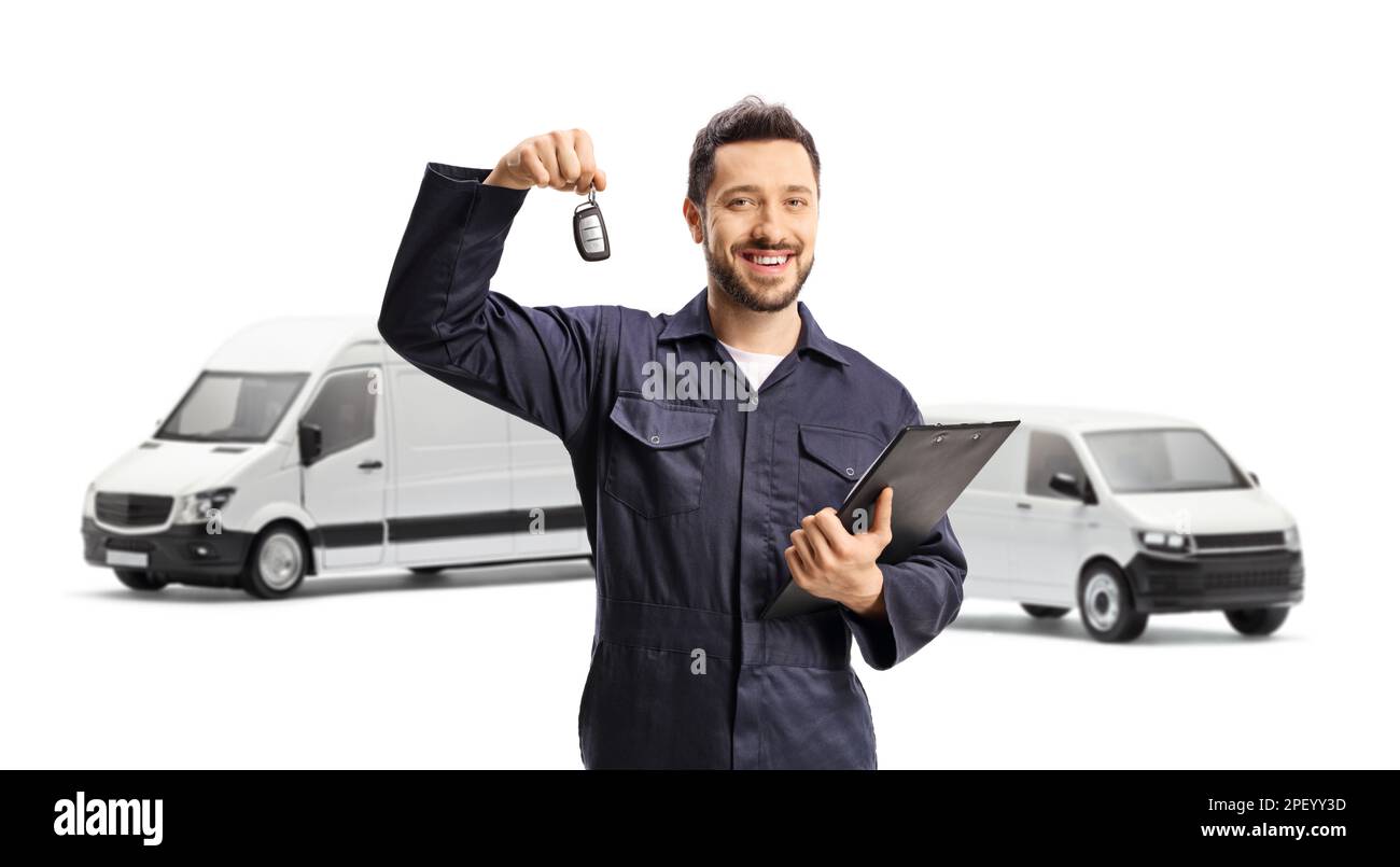 Auto mechanic holding a vehicle key in front of two white vans isolated ...