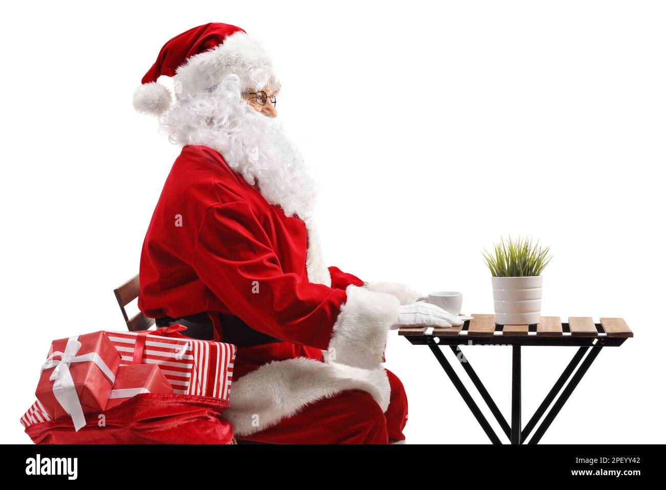 Santa claus sitting at a coffee table isolated on white background ...