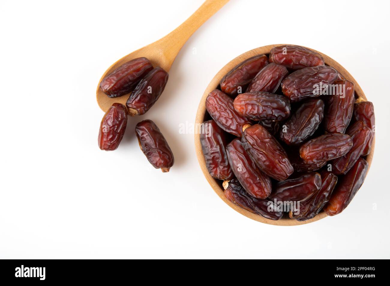 Date fruits in wooden bowl,on white background,top view Stock Photo - Alamy
