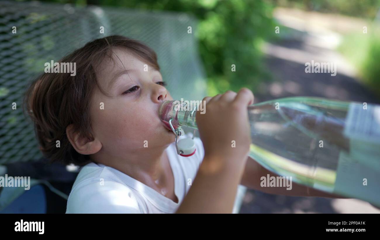 Child drinks water during hot summer day. Little boy gulping from glass ...