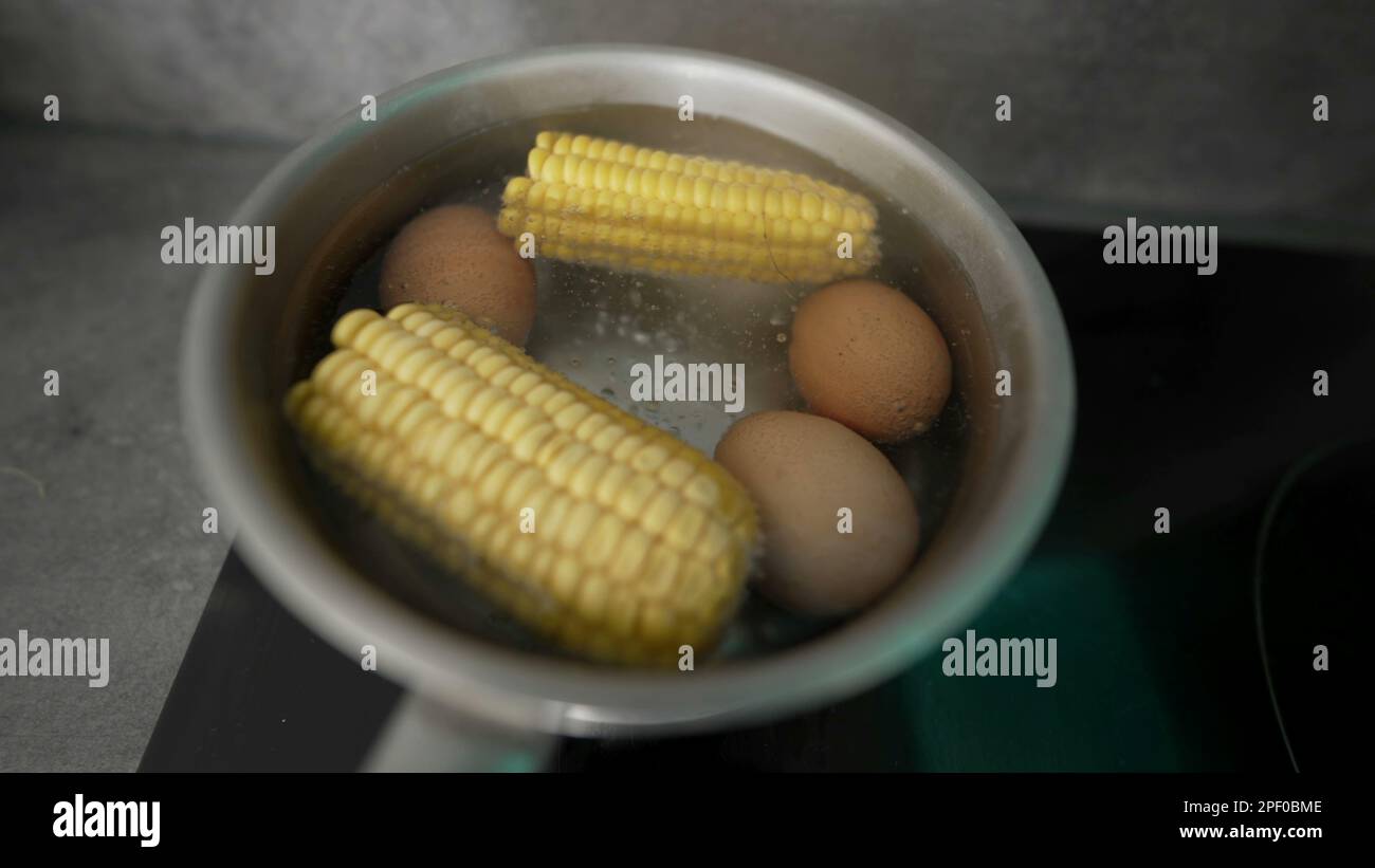 Food boiling inside pan. Cooking corn and eggs in hot water. nutritious ...