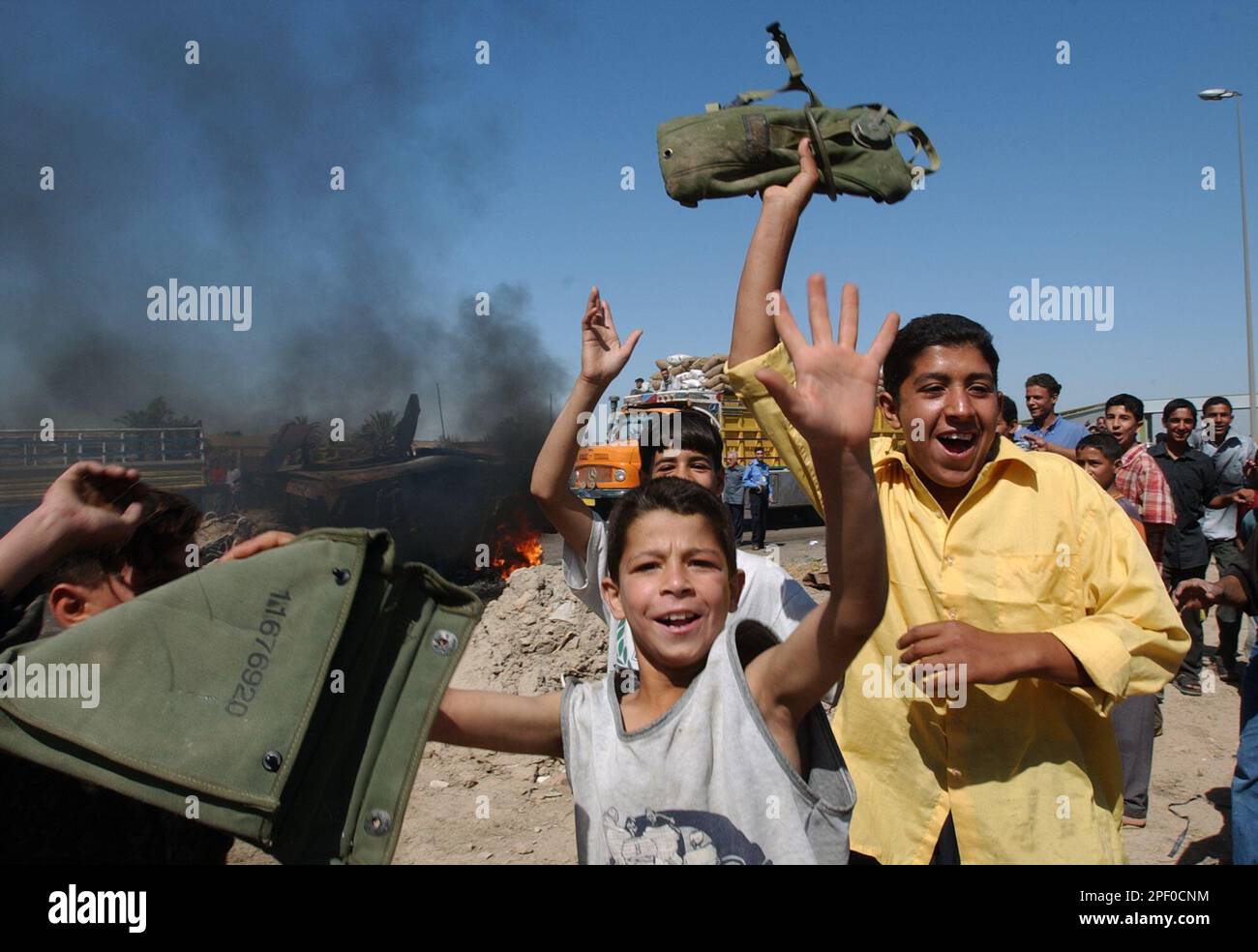 Iraqis celebrate holding U.S. Army equipment as they loot a burned out ...