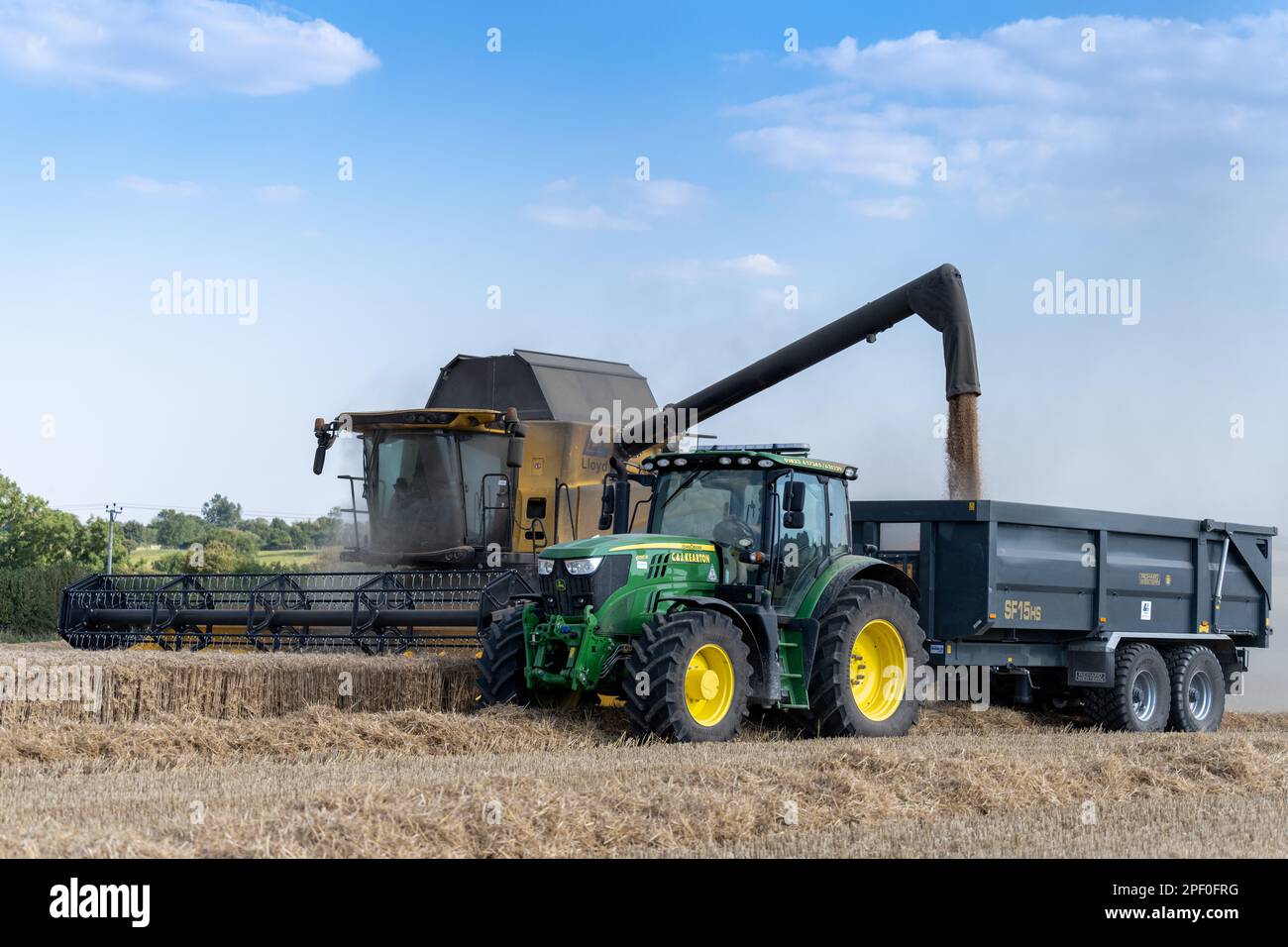 New Holland combine filling trailer with grain as it drives alongside ...
