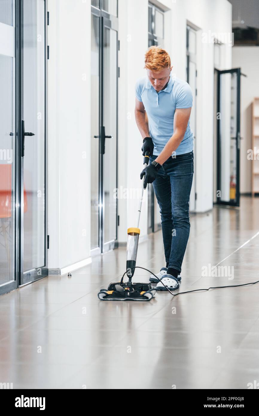 Young man works in the modern office. Uses vacuum cleaner Stock Photo ...