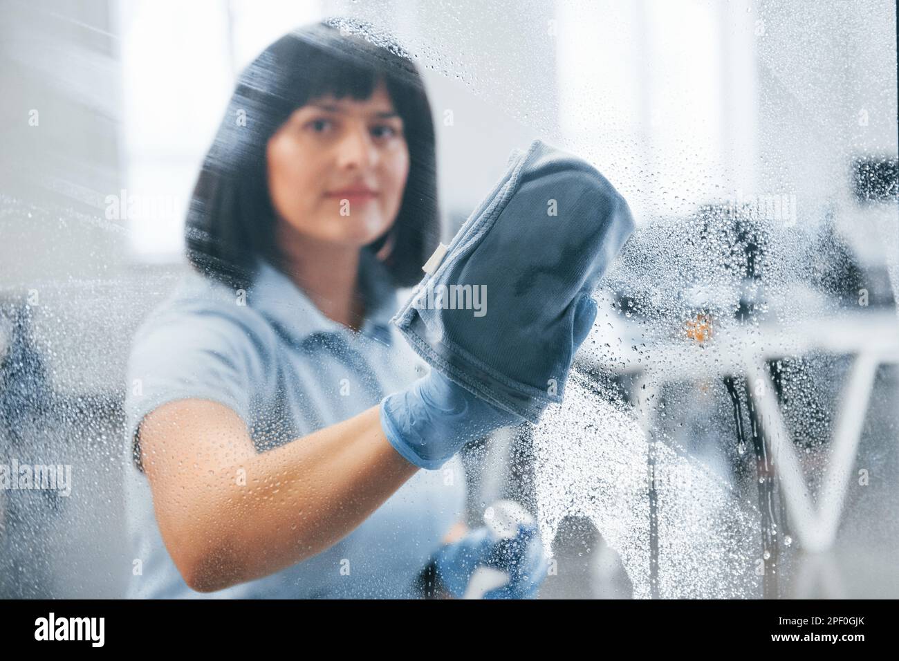 Woman cleaning dirty window by using towel. View through the glass ...