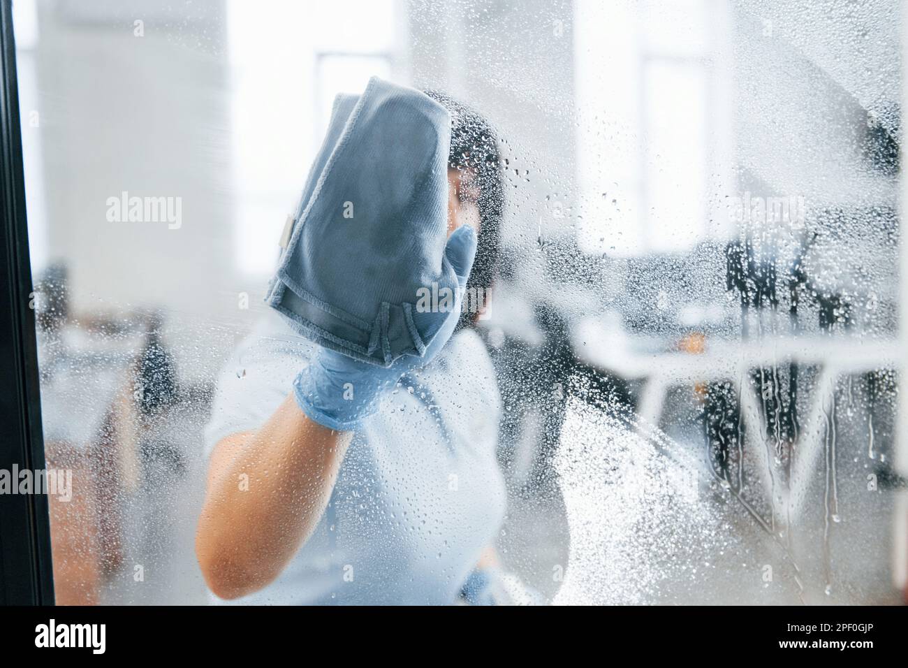 Woman cleaning dirty window by using towel. View through the glass ...