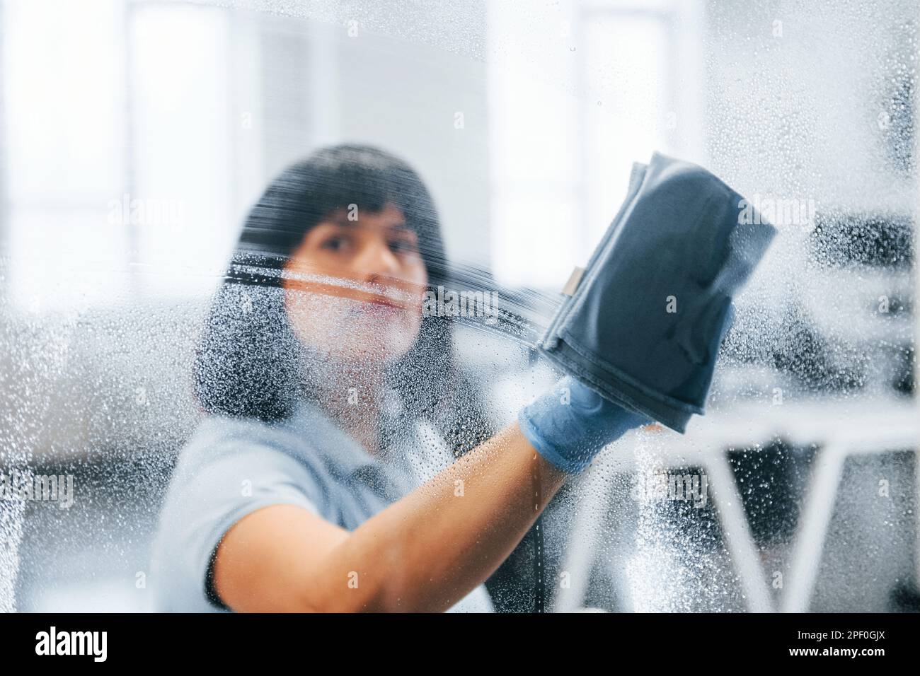 Woman cleaning dirty window by using towel. View through the glass ...
