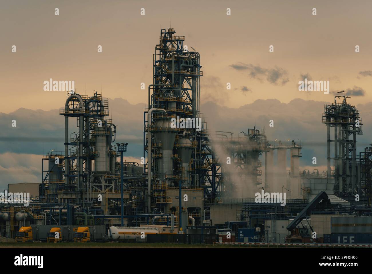 A sprawling industrial factory, featuring a number of large pipes and ...