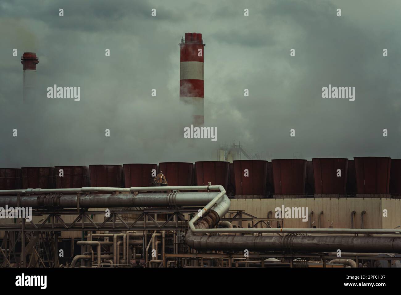 A large industrial factory, featuring a chimney emanating smoke, and ...