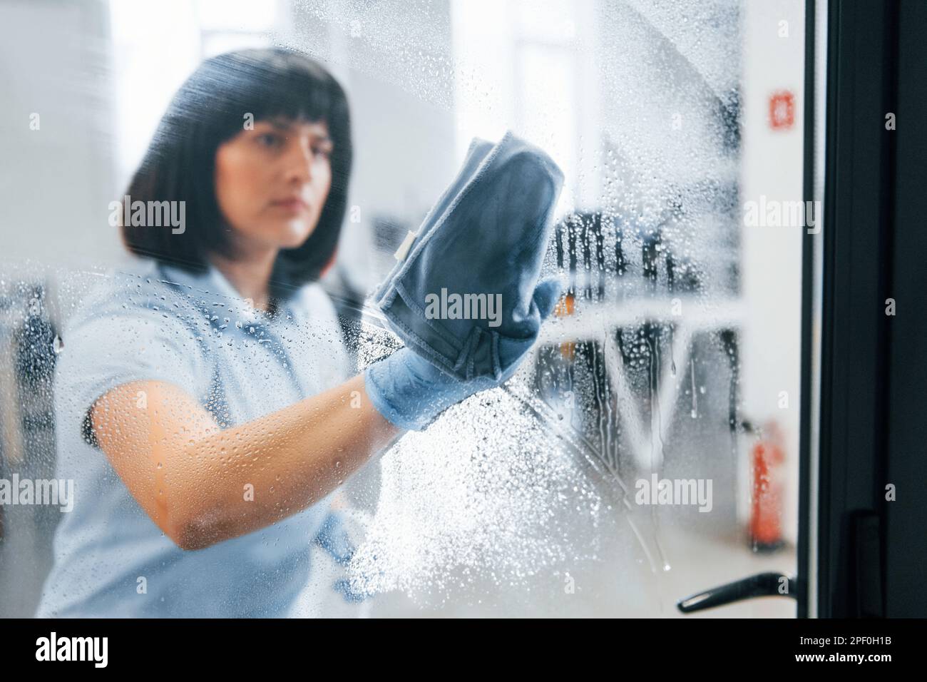 Woman cleaning dirty window by using towel. View through the glass ...