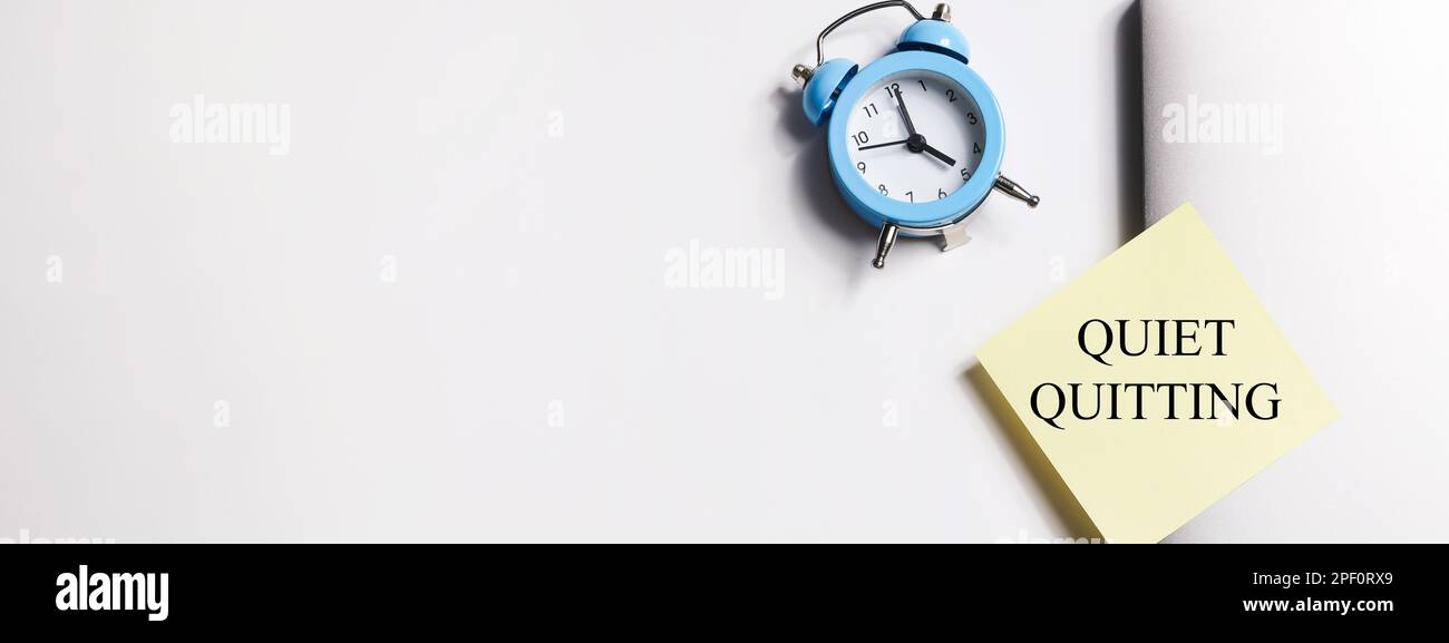 quote 'Quiet quitting' on yellow sticker on computer with clock . work ...
