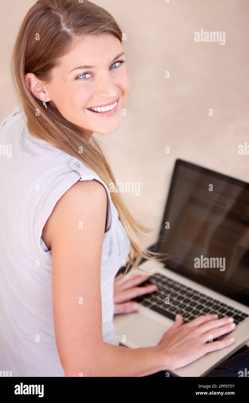 Using her laptop from the comfort of home. Rear view of a lovely young ...