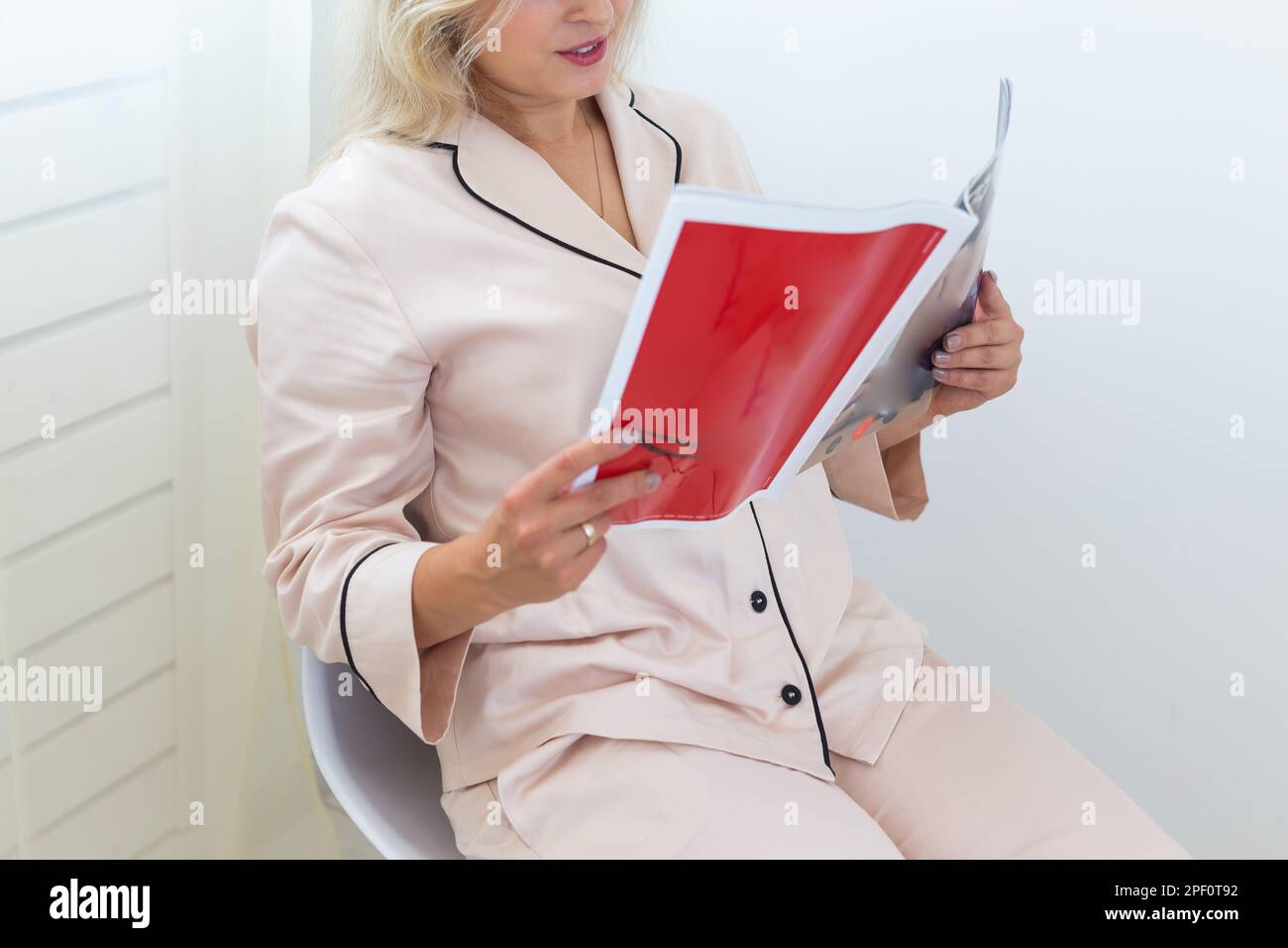 Woman wears pajama reads magazine in living room. Homewear, sleepwear ...