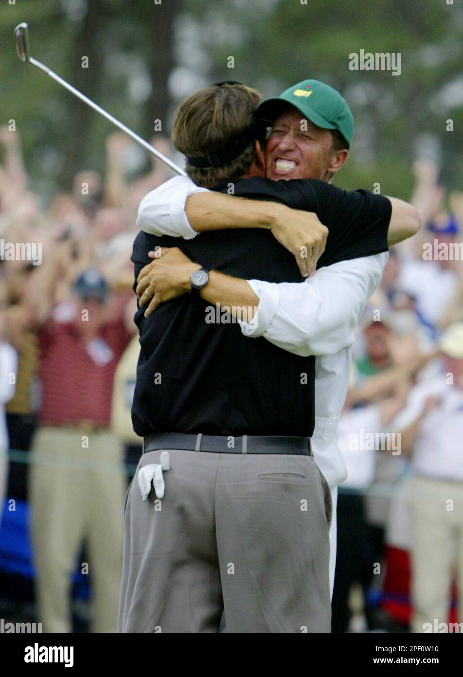 Phil Mickelson is hugged by his his caddie Jim MacKay after winning the Masters golf tournament ...
