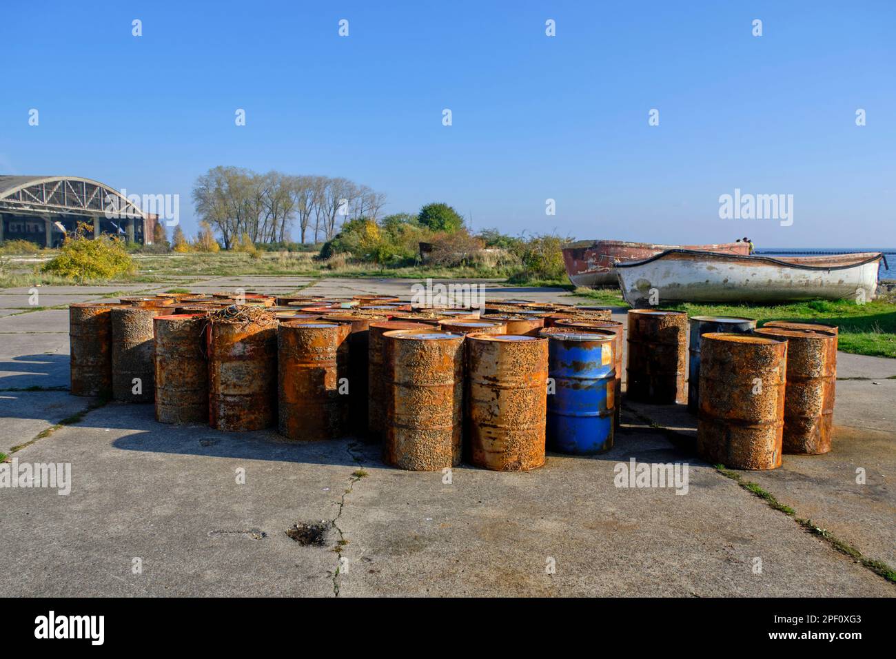 Rusty fuel barrels shore against background old hangar and boats Stock ...