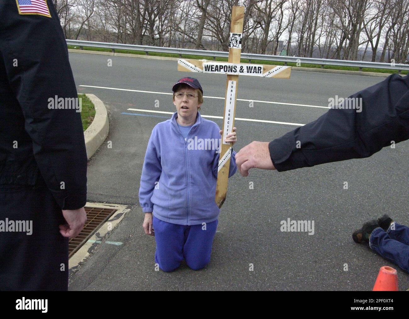 A supporter of the Brandywine Peace Community kneels and holds a wooden ...