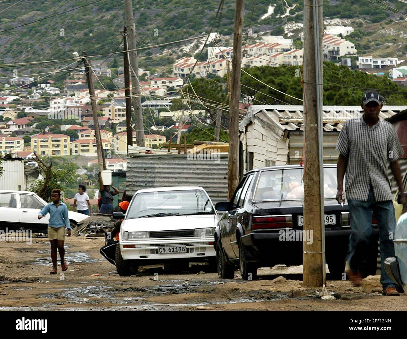 Squatters make their way through a muddy street in the Imizamo Yethu ...