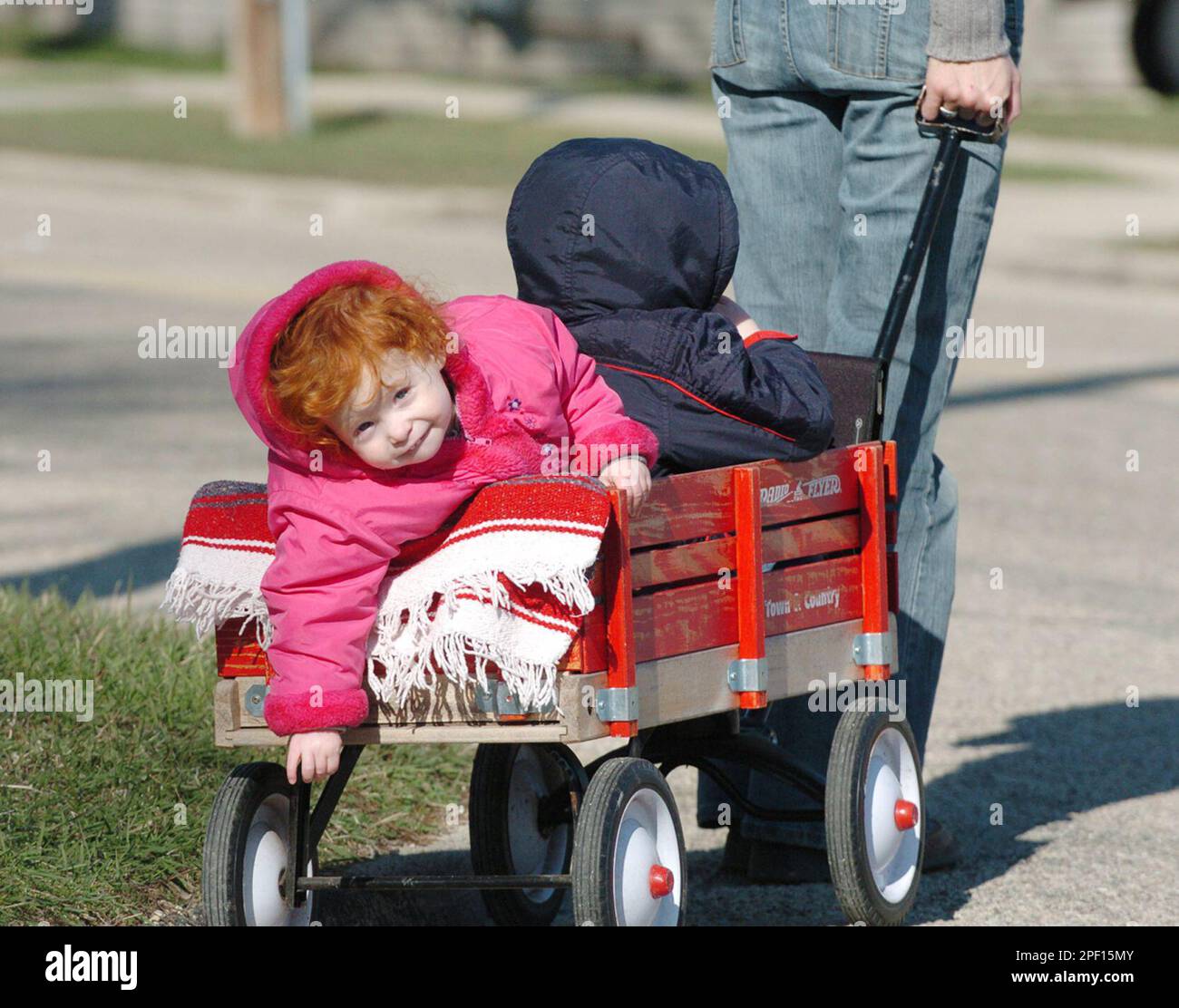 Abbey Luedtke, 2, leans out the back of a wagon as she goes for a walk ...