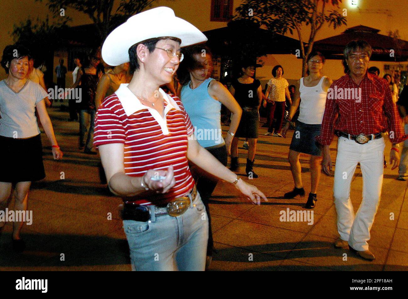 A line dancer smiles as she dances in timed steps to the music, in ...