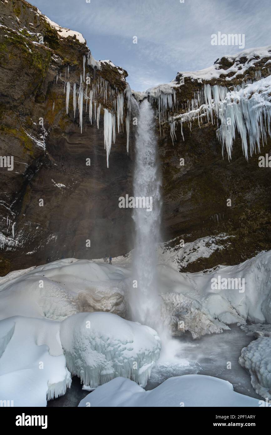 Group of mountaineering tourists behind the frozen Kvernufoss waterfall ...