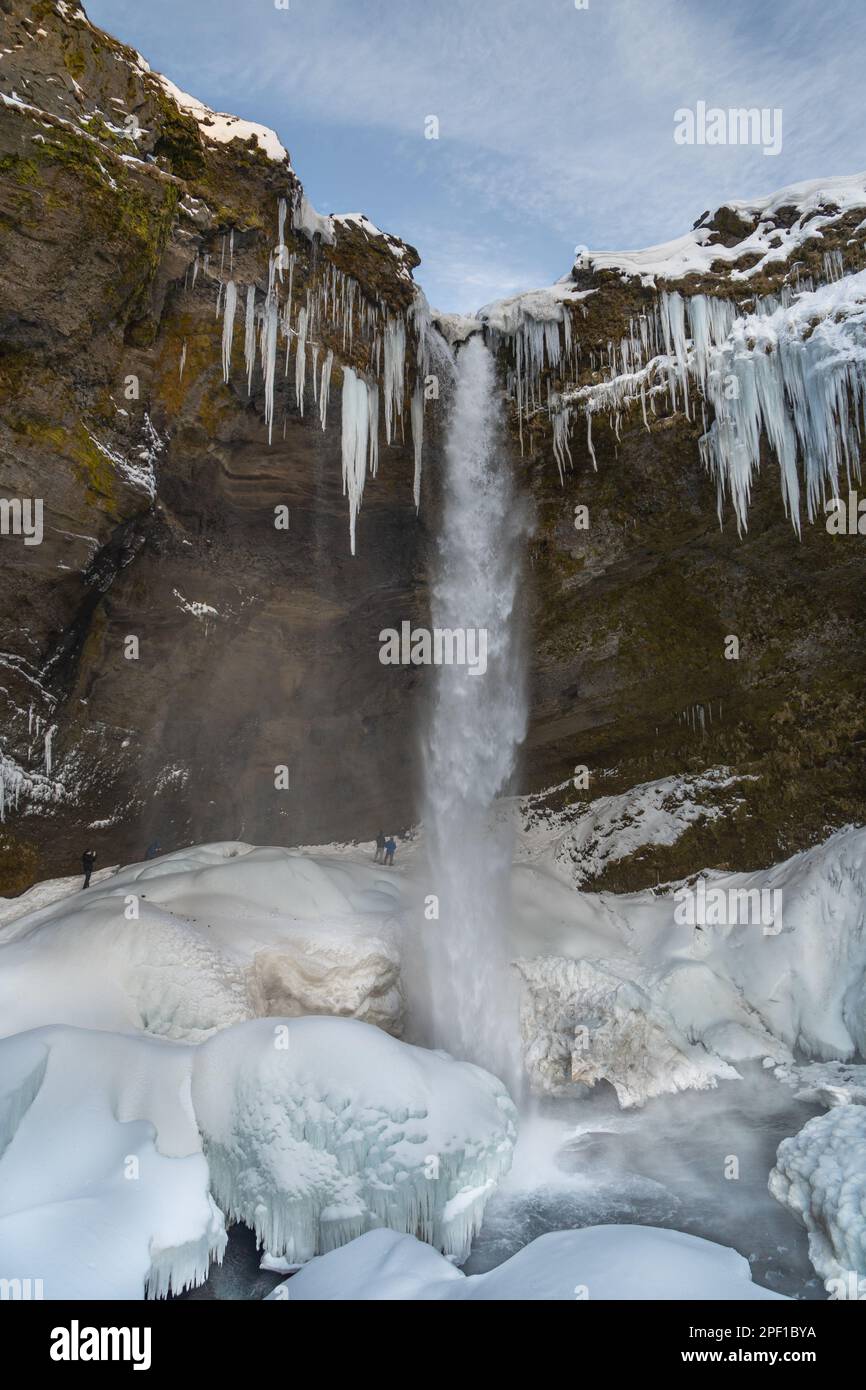 Group of mountaineering tourists behind the frozen Kvernufoss waterfall ...