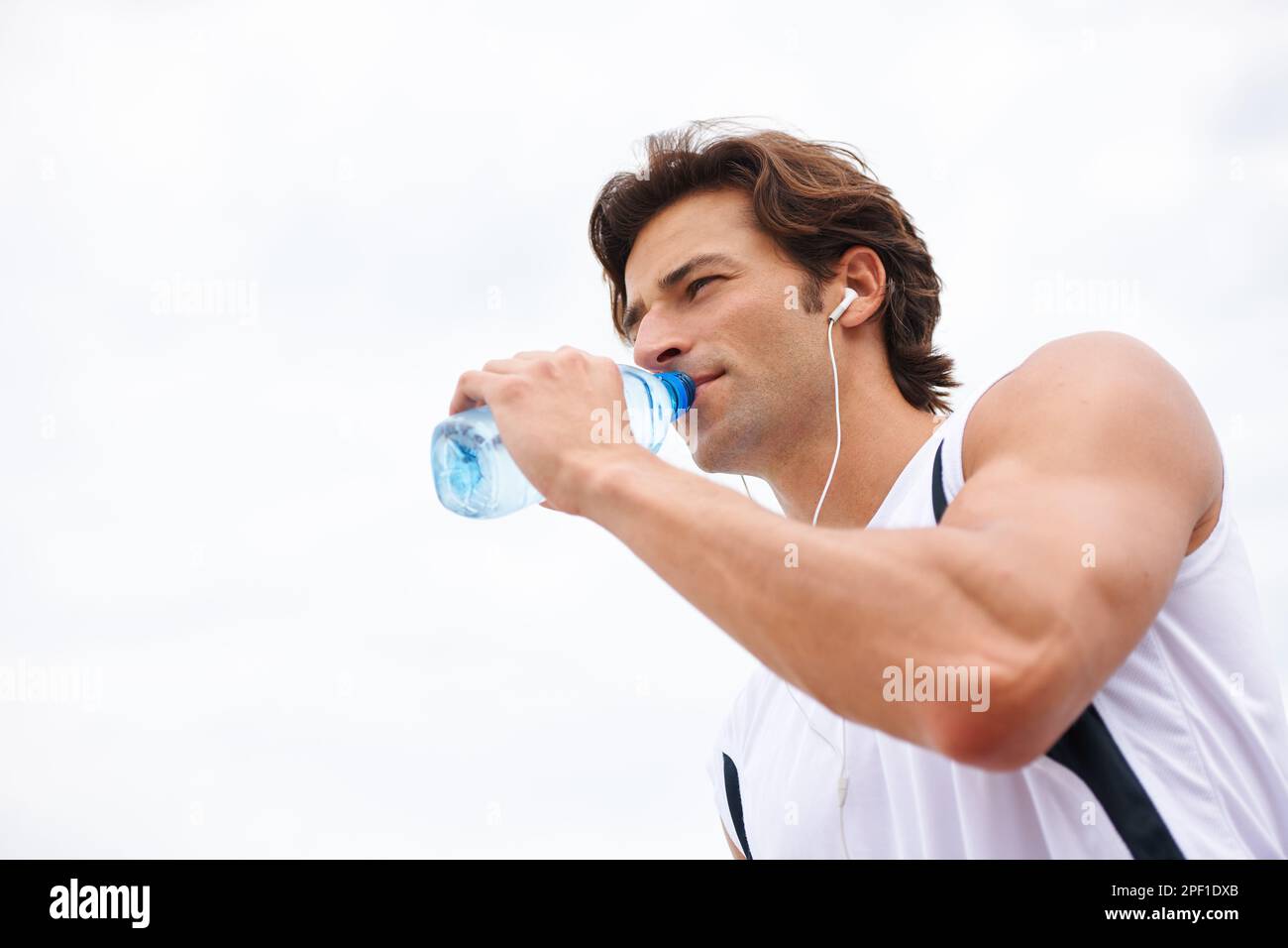 Rehydrating. a handsome young man taking a drink of water while working ...