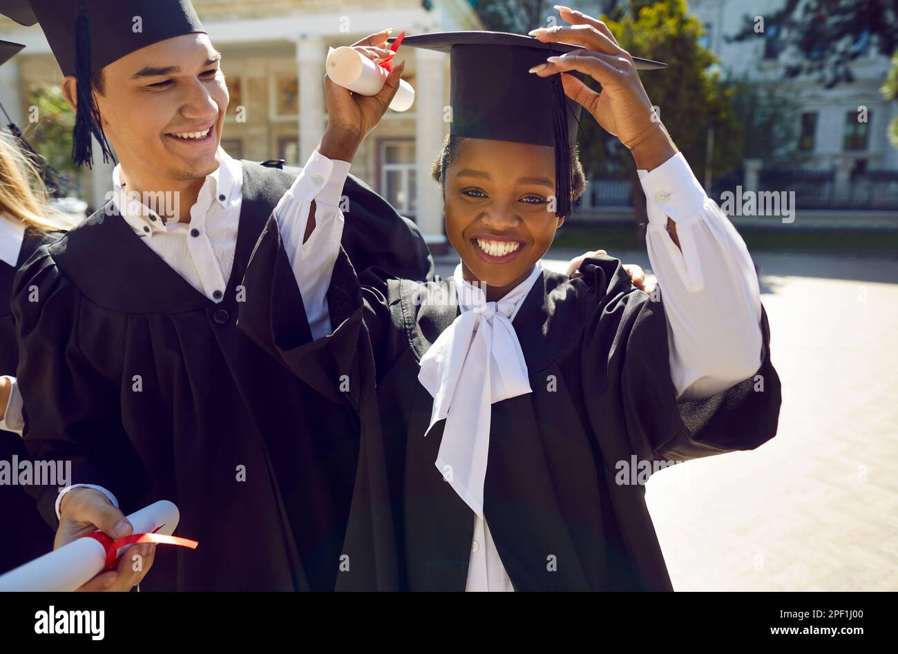 Portrait of happy African American girl in cap and gown having fun on ...
