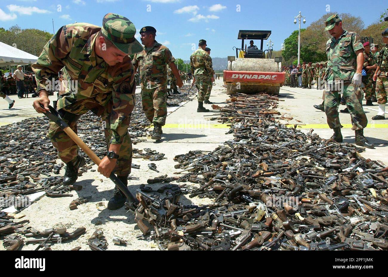 Army soldiers shovel weapons in front of a crushing machine at Fort ...