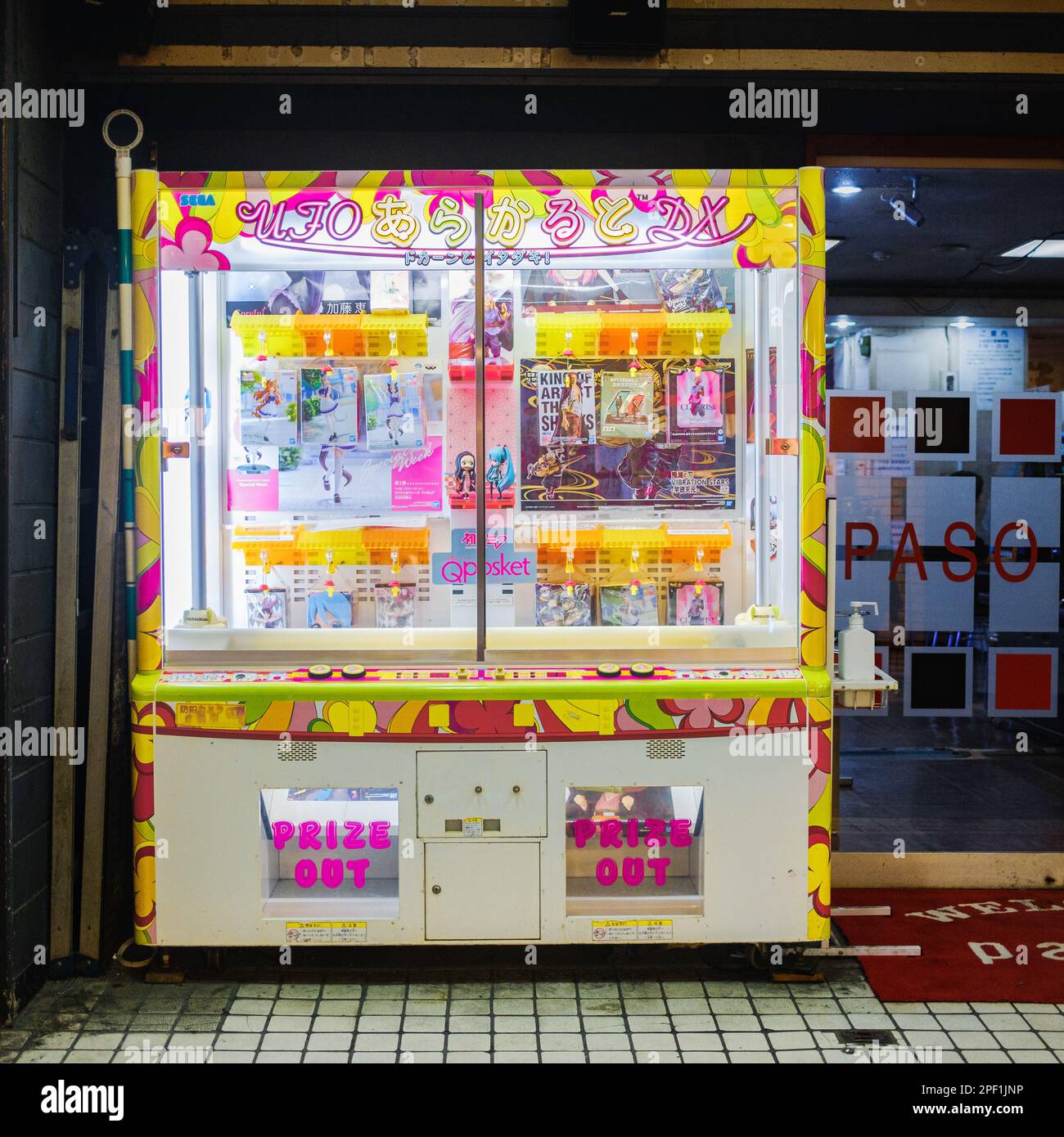 A lone “UFO Catcher” (claw crane arcade machine) tucked in a dark ...