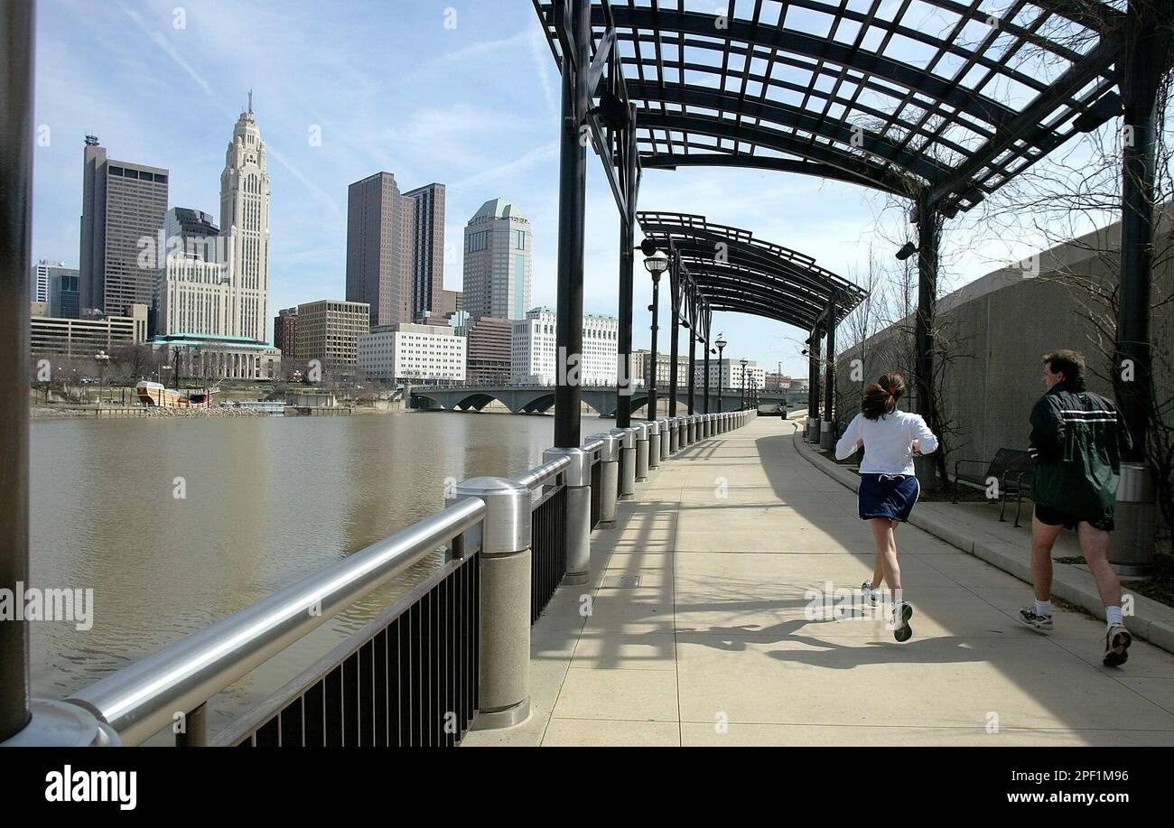 Two joggers enjoy the sunshine as they run next to the Scioto river ...
