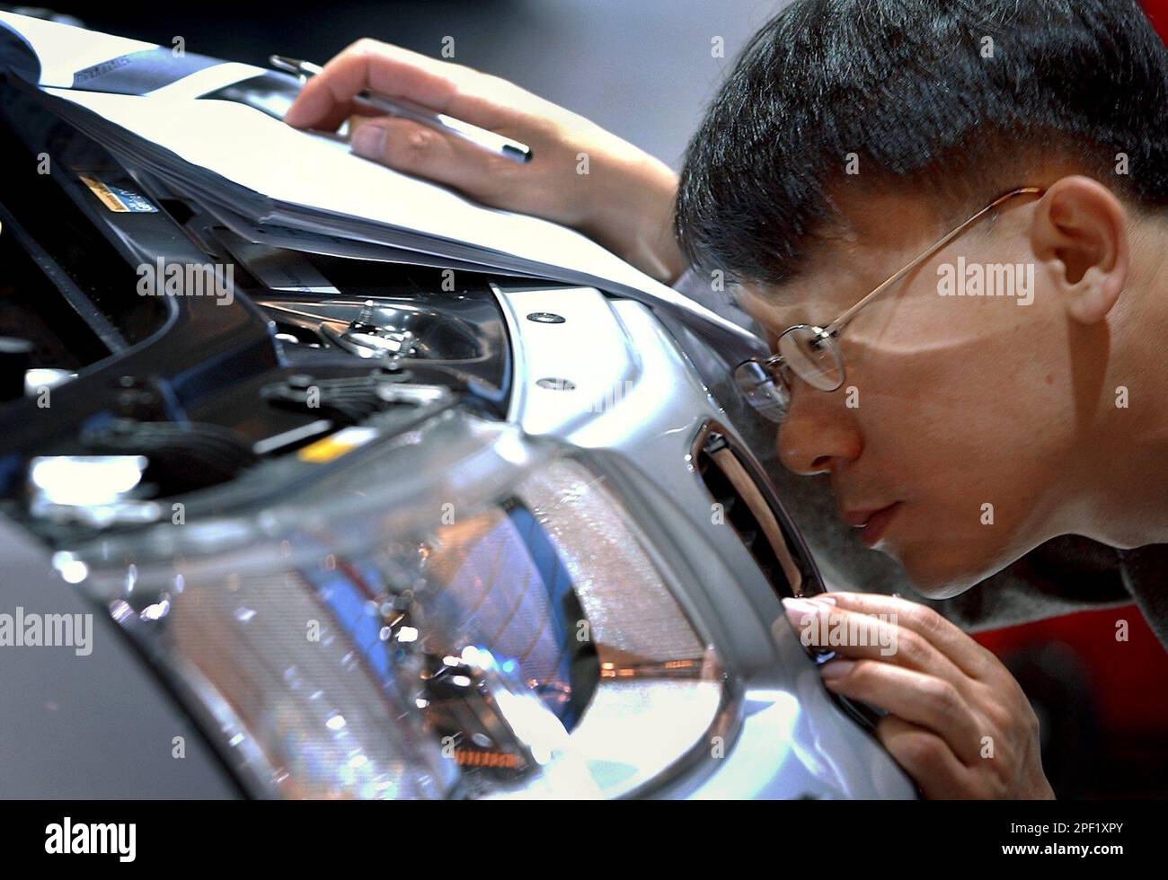 A journalist peeks under the engine hood of a Saab at the 74th Geneva ...