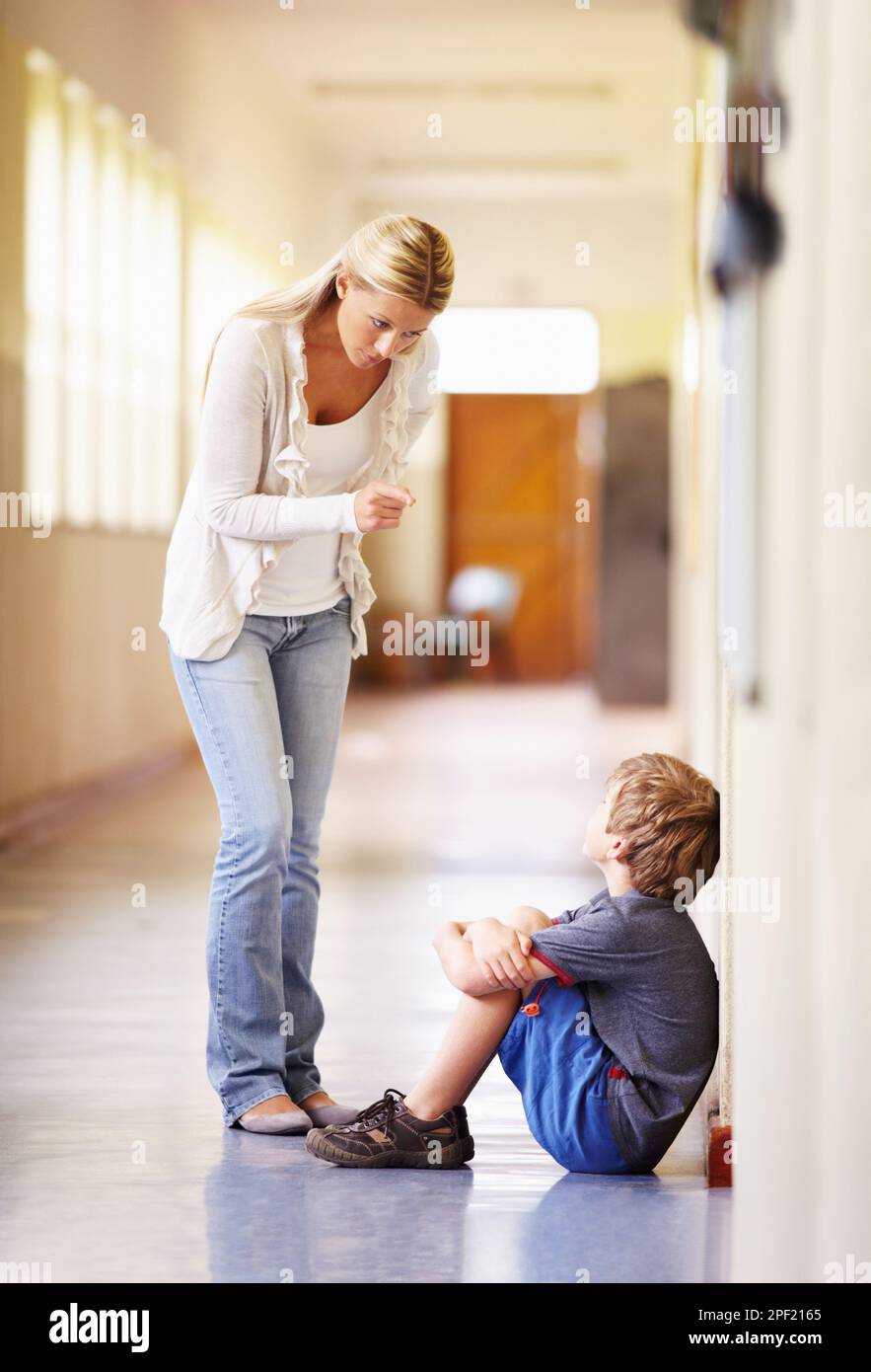 Reprimanding his actions. A teacher scolding a young boy in the hallway ...