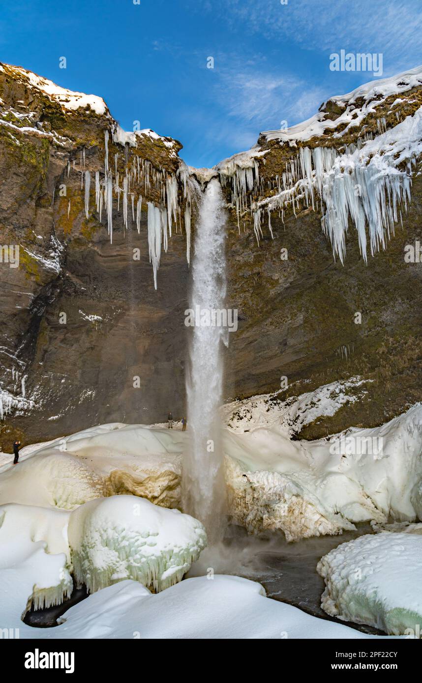 Group of mountaineering tourists behind the frozen Kvernufoss waterfall ...