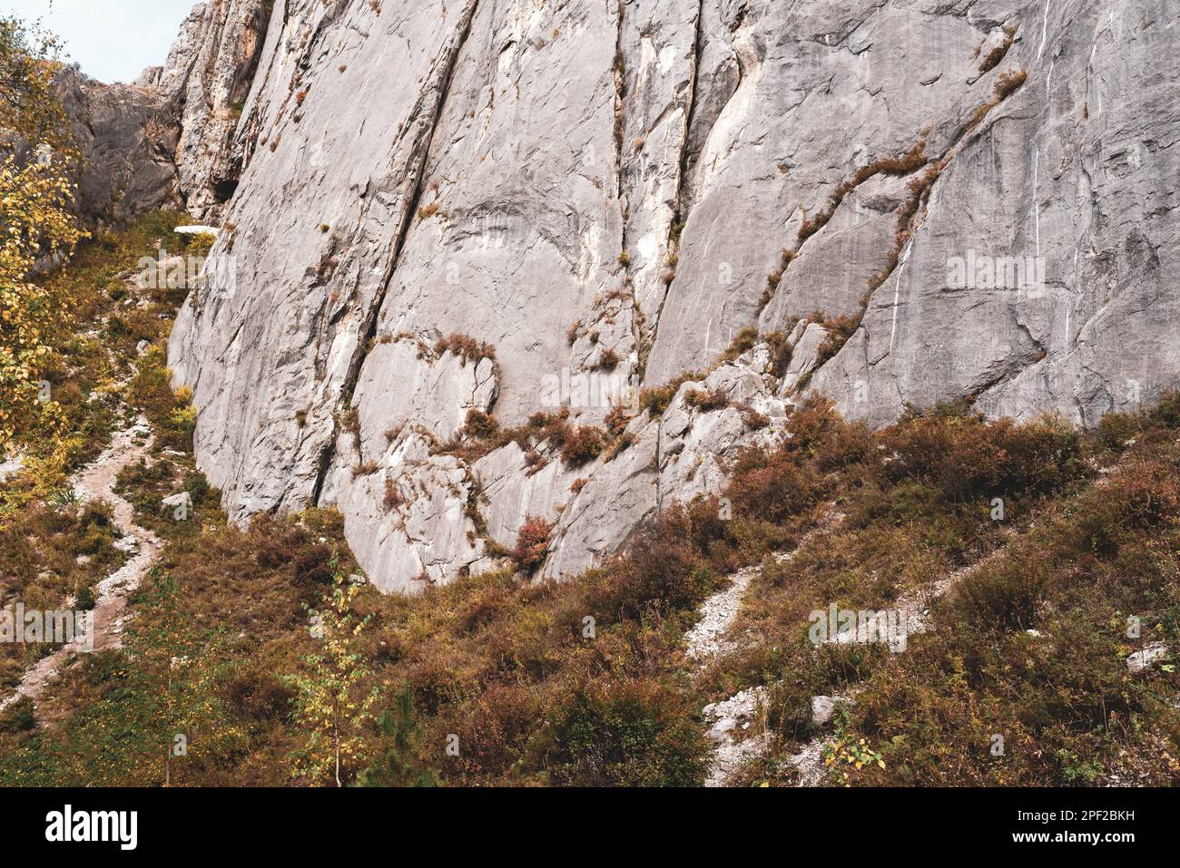 The trail without people goes to a cave in a gorge between smooth rocky ...