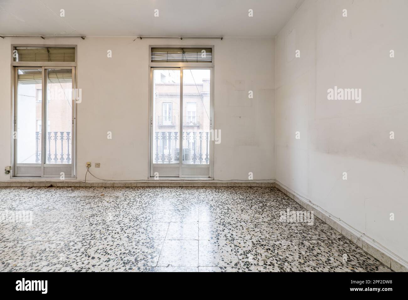 Empty living room of a house with terrazzo floors with black dots, two ...