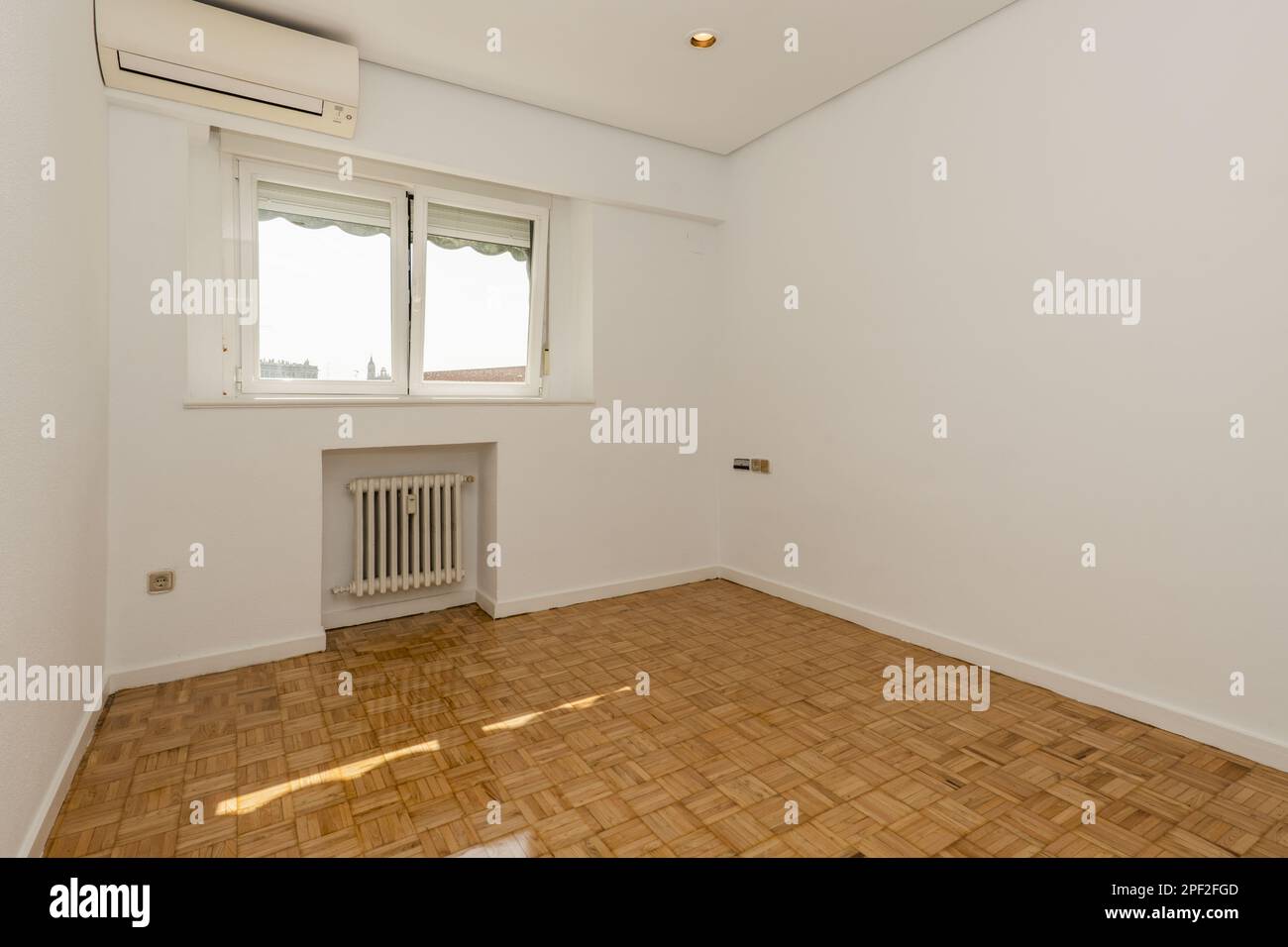 Empty room with tilt-and-turn windows, air conditioner and cast-iron ...