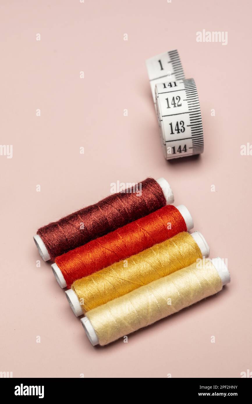 Still life with colored threads with tape measure on a plain pink ...