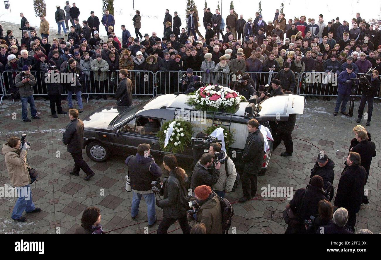 Fans stand behind a barrier as the hearse carrying the coffin of late ...