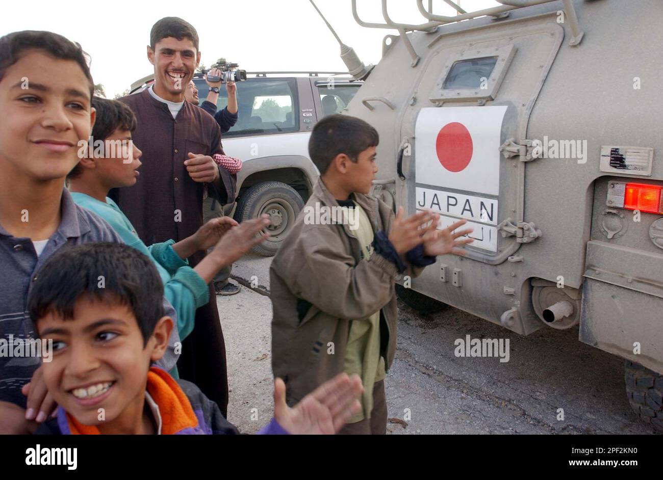 Iraqi boys clap their hands to a Japanese army vehicle, in Khider, near ...