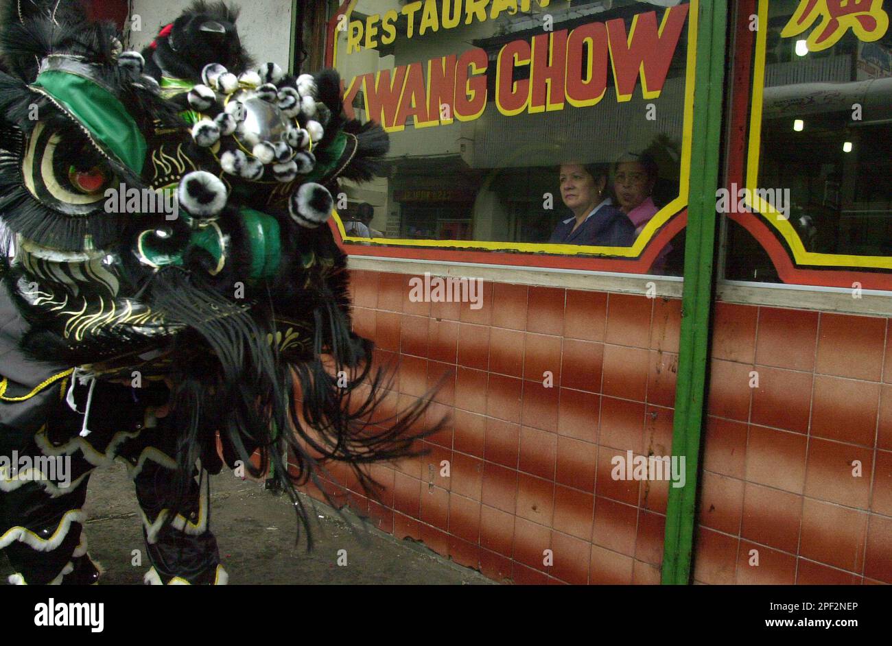 Onlookers watch through a window as a Chinese dragon performance passes ...