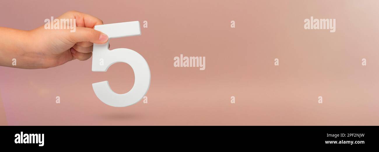 Number five in hand. Hand holding white number 5 on red background with ...
