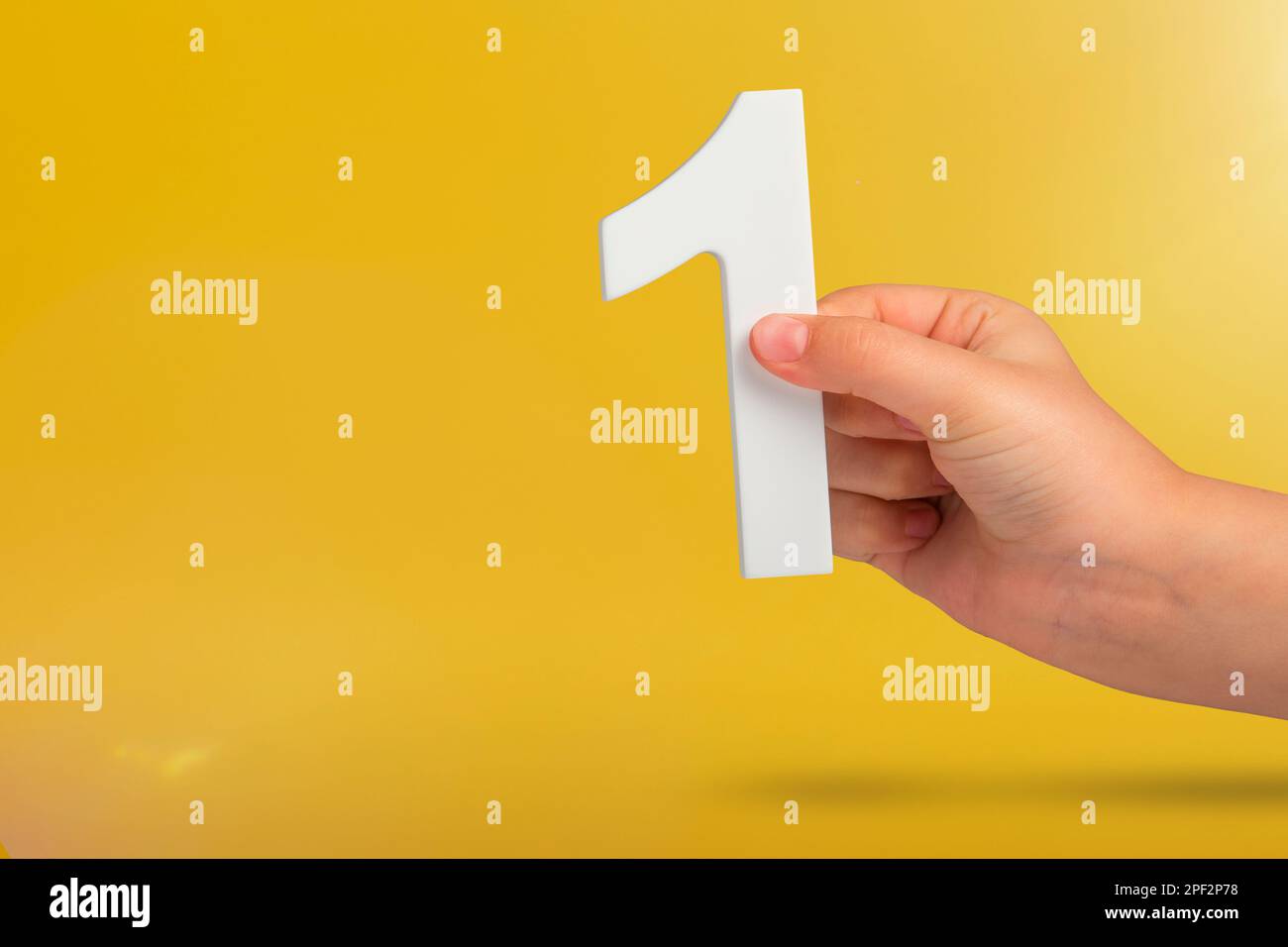 Number one in hand. A hand holds a white number one on a yellow ...