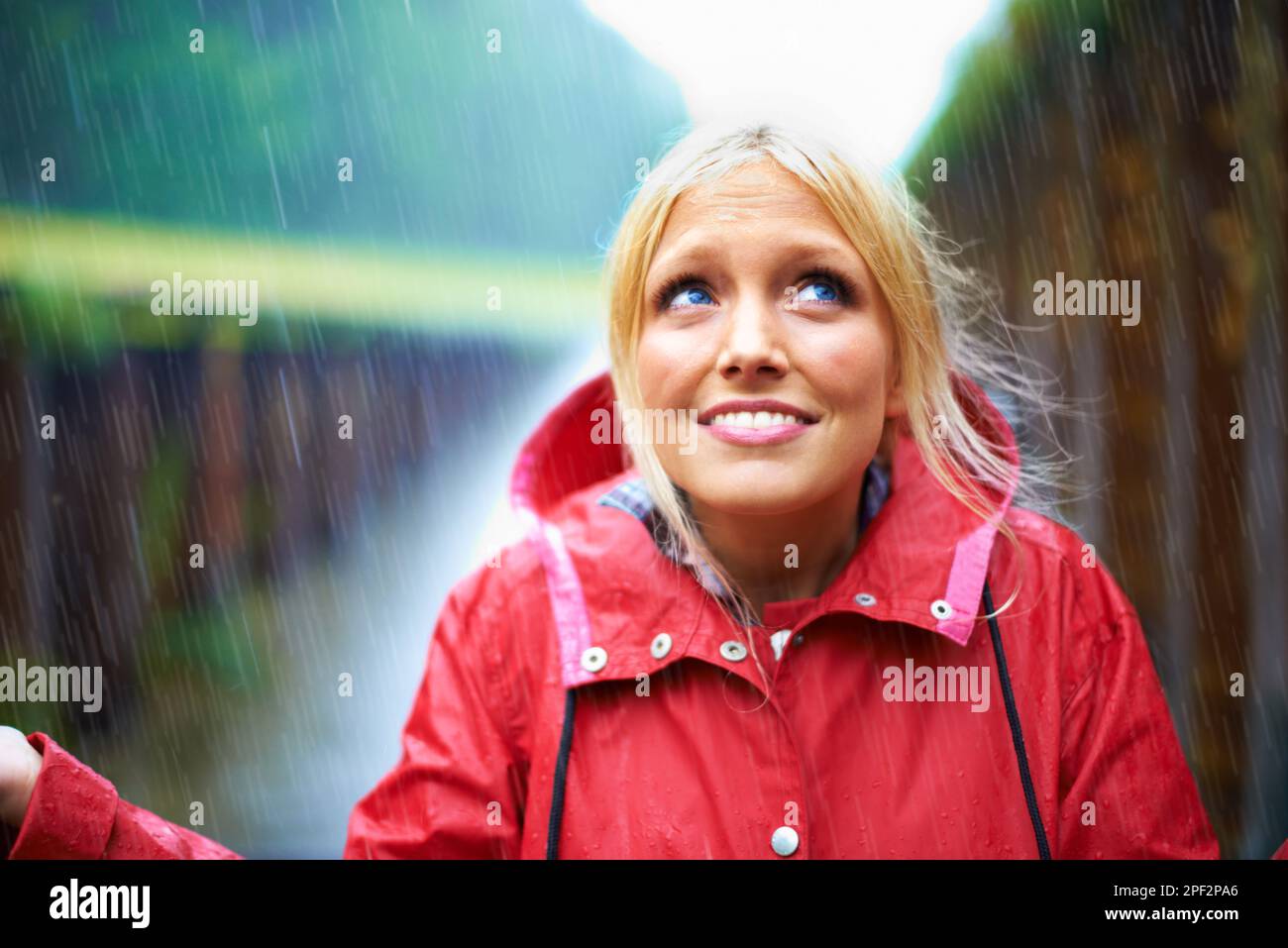 Its started raining. Gorgeous young blonde woman wearing a red raincoat ...