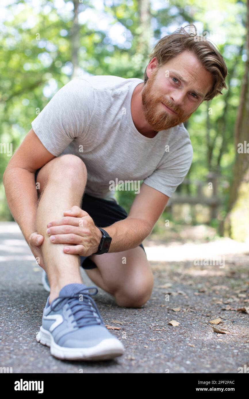 male runner has a leg cramp Stock Photo - Alamy