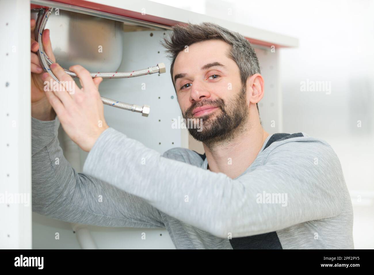 young plumber working with pipe wrench in kitchen Stock Photo - Alamy